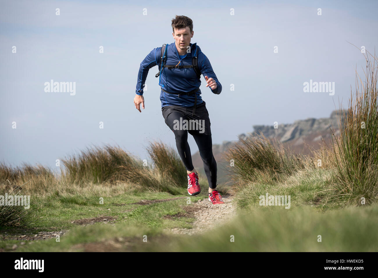 Male runner running on path at Stanage Edge, Peak District, Derbyshire ...