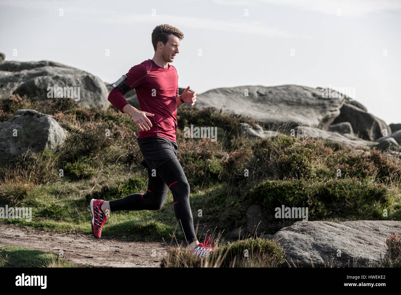 Male runner running down path from Stanage Edge, Peak District ...