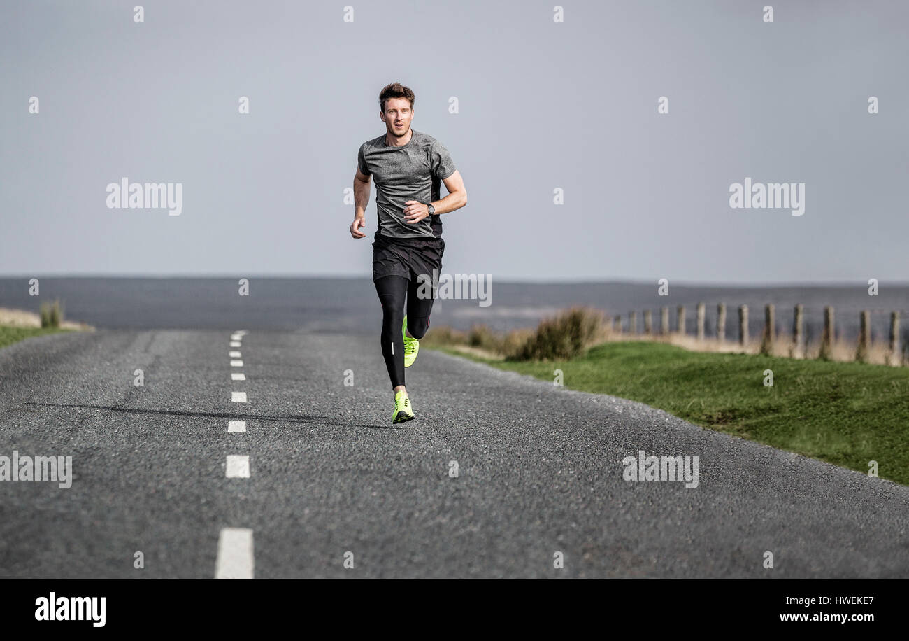 Male runner running along rural moorland road Stock Photo - Alamy