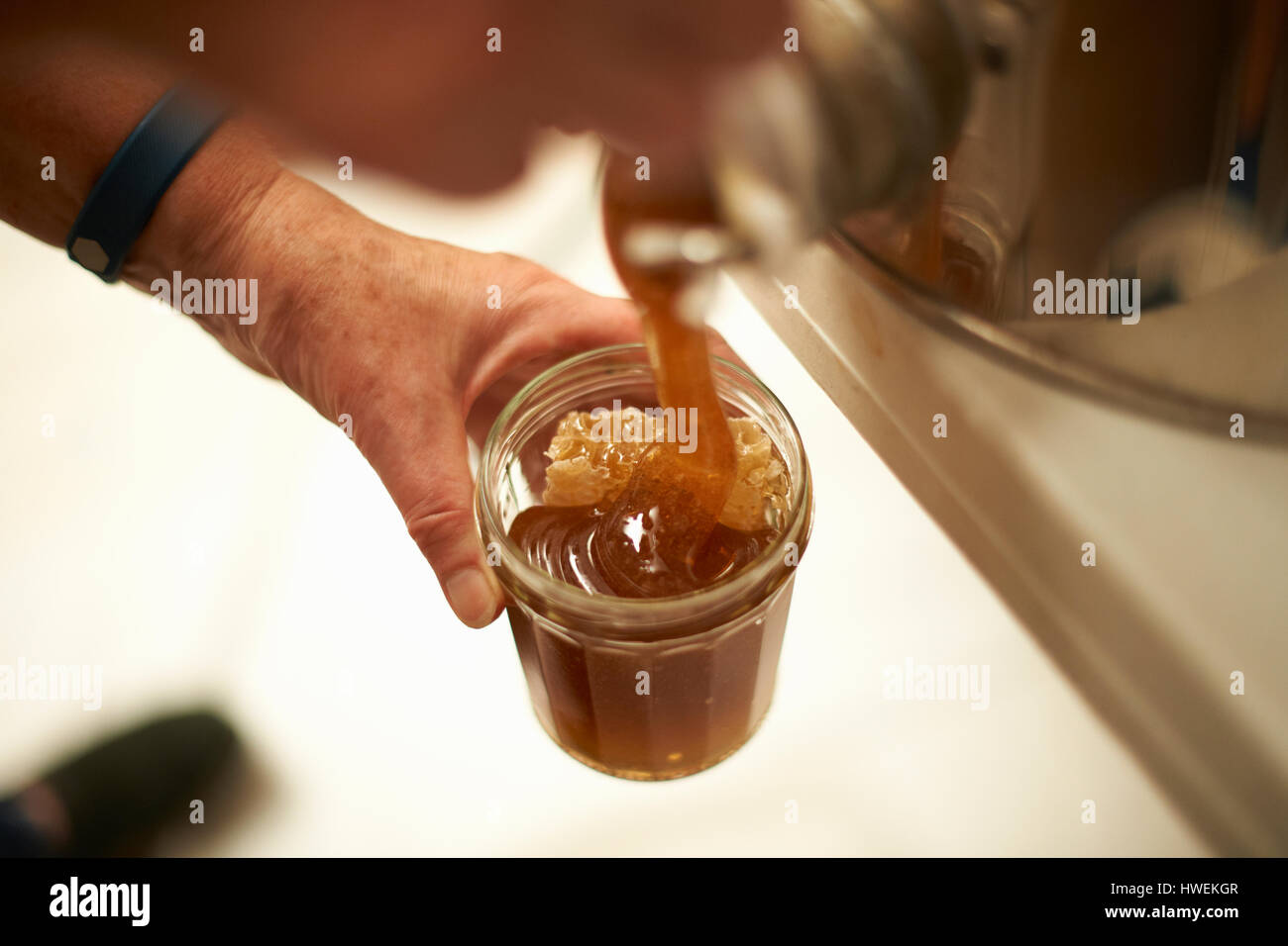 Hands of female beekeeper pouring honey into jar from kitchen vat Stock ...