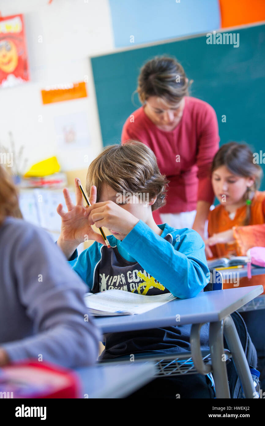 Primary schoolboy counting on fingers in classroom Stock Photo - Alamy