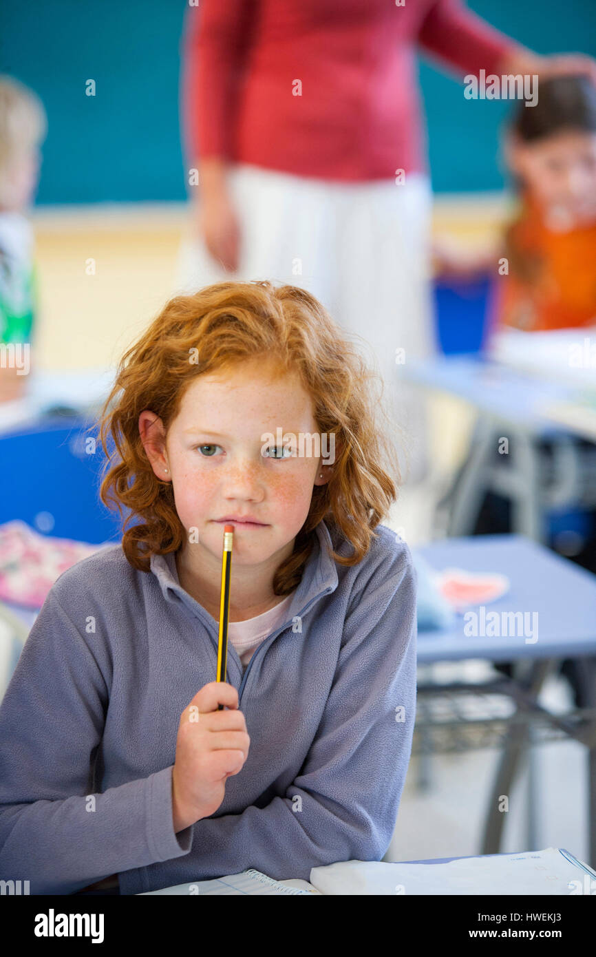 Primary schoolgirl thinking in classroom Stock Photo - Alamy