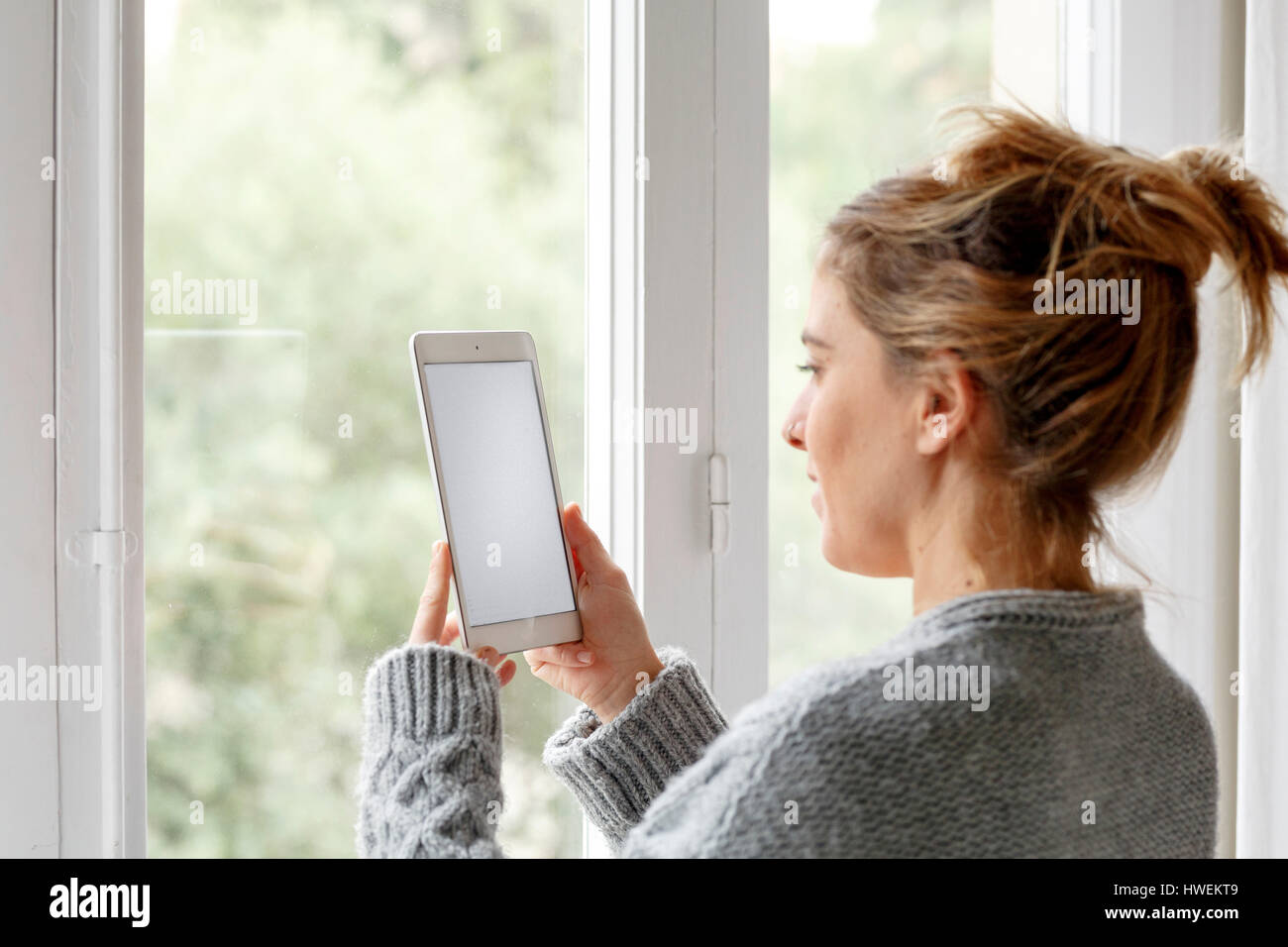 Woman at home, standing beside window, using digital tablet Stock Photo ...