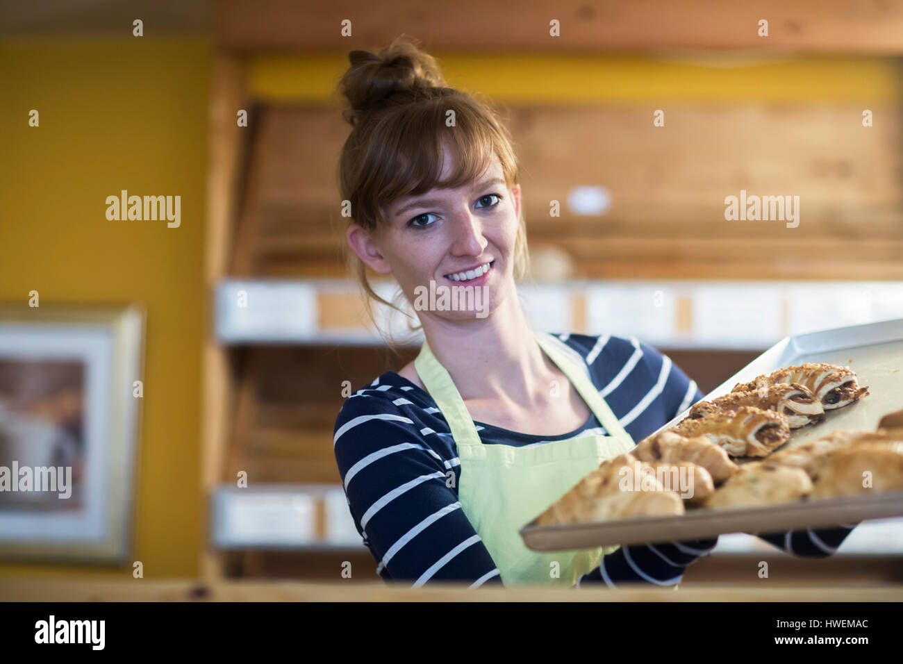 Portrait of young woman in bakery, holding tray of pastries Stock Photo ...