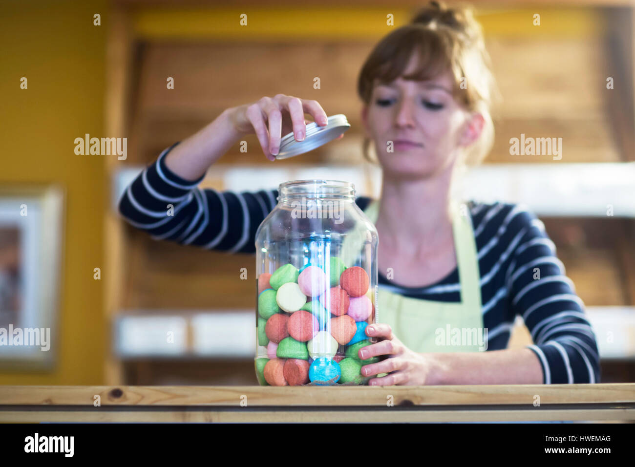 Young woman in food shop, opening jar of sweet food Stock Photo - Alamy