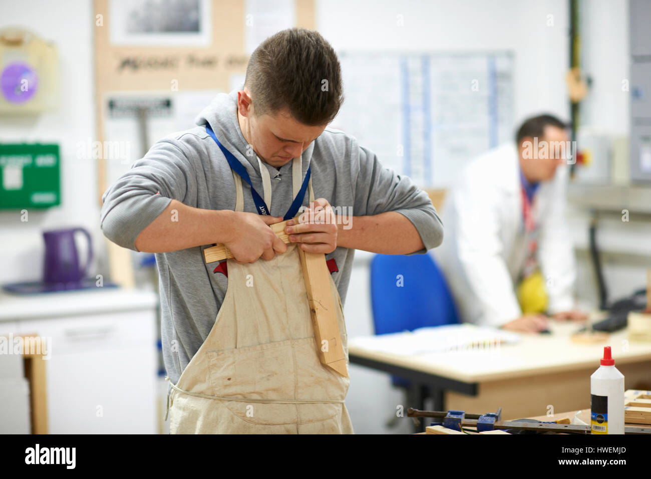 Male teenage carpentry student pushing wood joints together in college ...