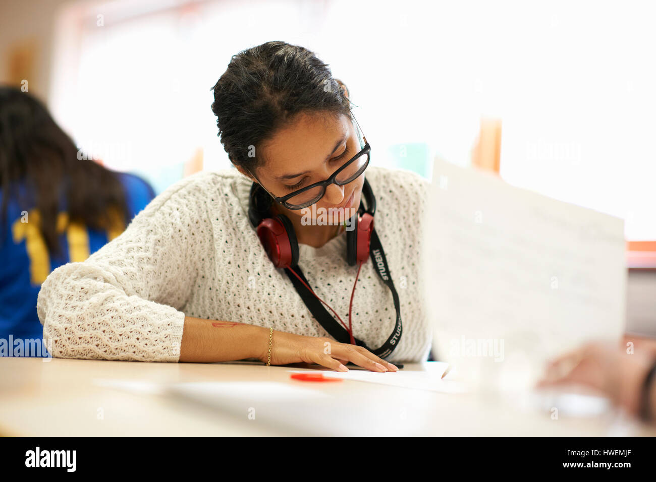 Young female student writing at desk in college classroom Stock Photo ...