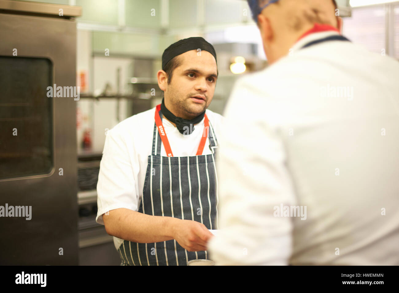 Chef lecturer explaining recipe to teenage catering student in college ...