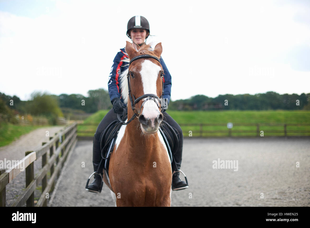 Young woman riding horse around paddock Stock Photo - Alamy