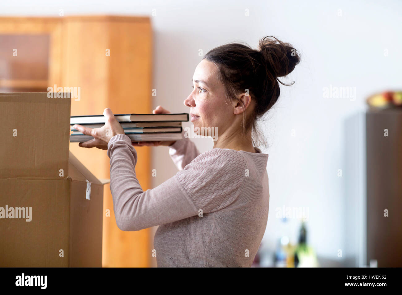 Woman packing books into cardboard box Stock Photo - Alamy