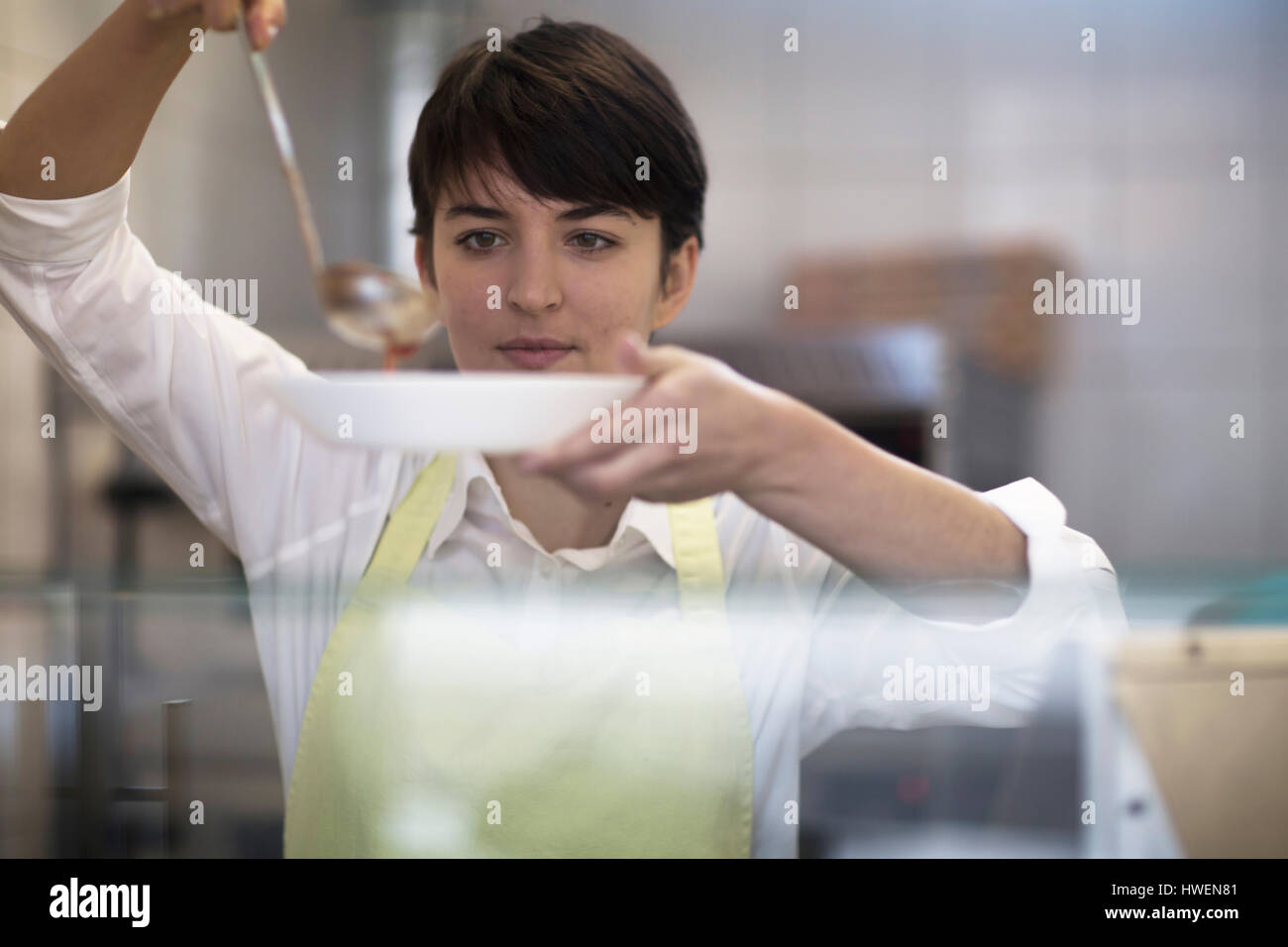 Young woman spooning food into bowl in fast food shop Stock Photo - Alamy