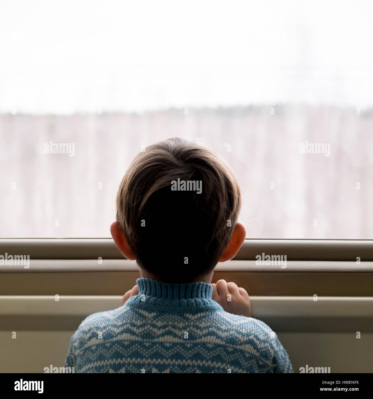 Rear view of boy looking out of window Stock Photo - Alamy