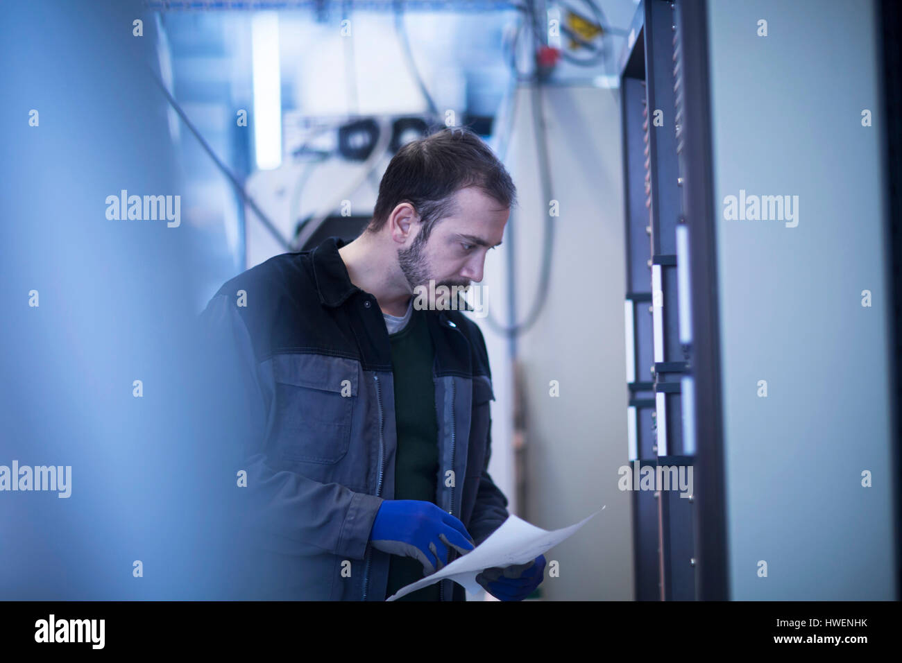 Engineer holding paperwork operating control panel Stock Photo - Alamy