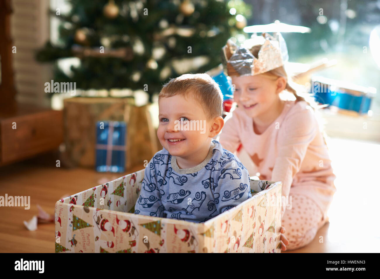 Girl pushing brother in cardboard box at christmas Stock Photo - Alamy