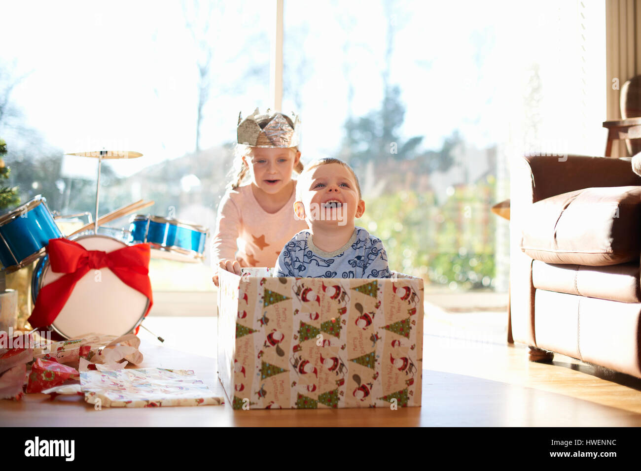 Girl pushing brother in cardboard box at christmas Stock Photo - Alamy