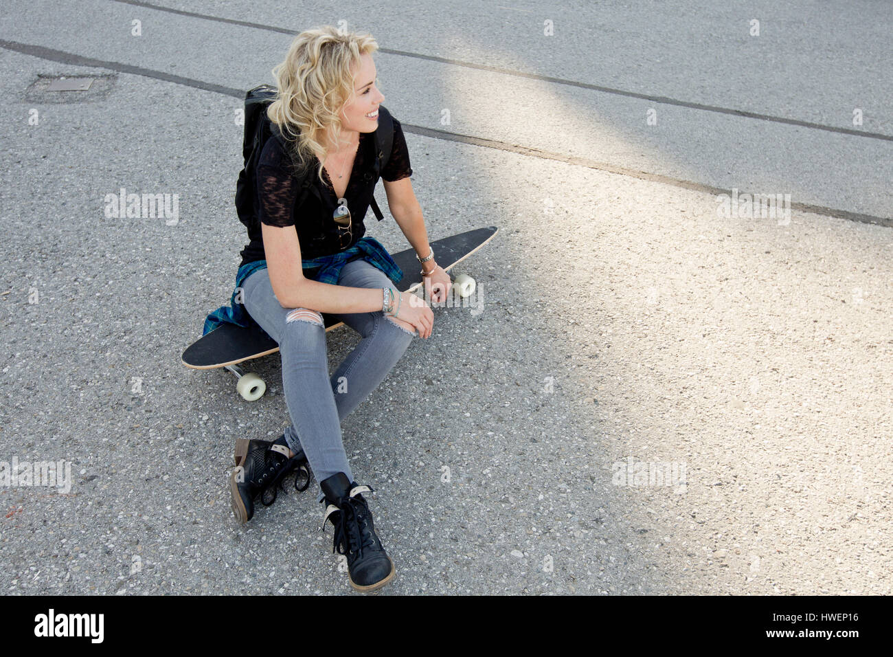 Female skateboarder sitting on skateboard Stock Photo - Alamy