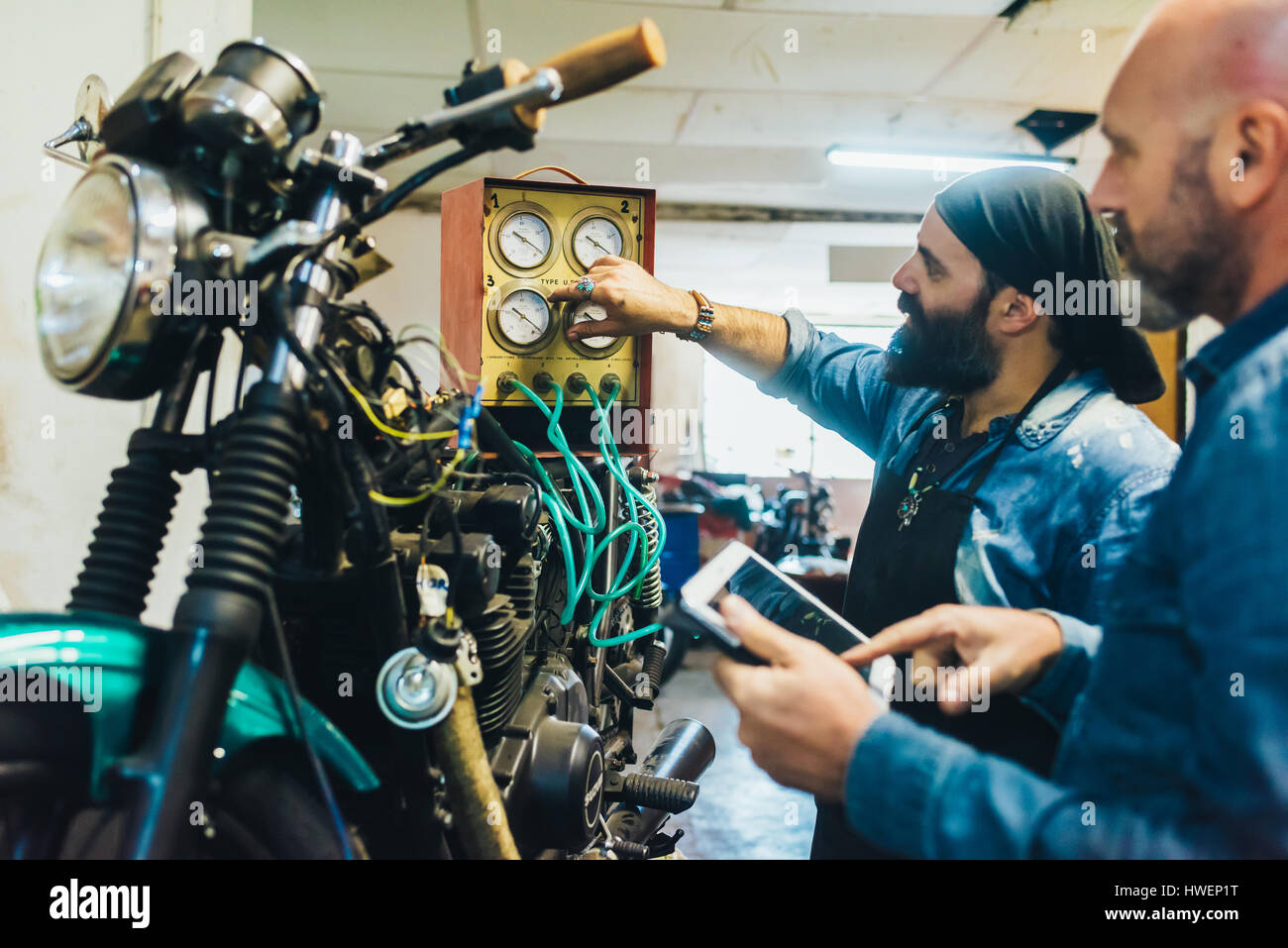 Two mature men, working on motorcycle in garage Stock Photo - Alamy
