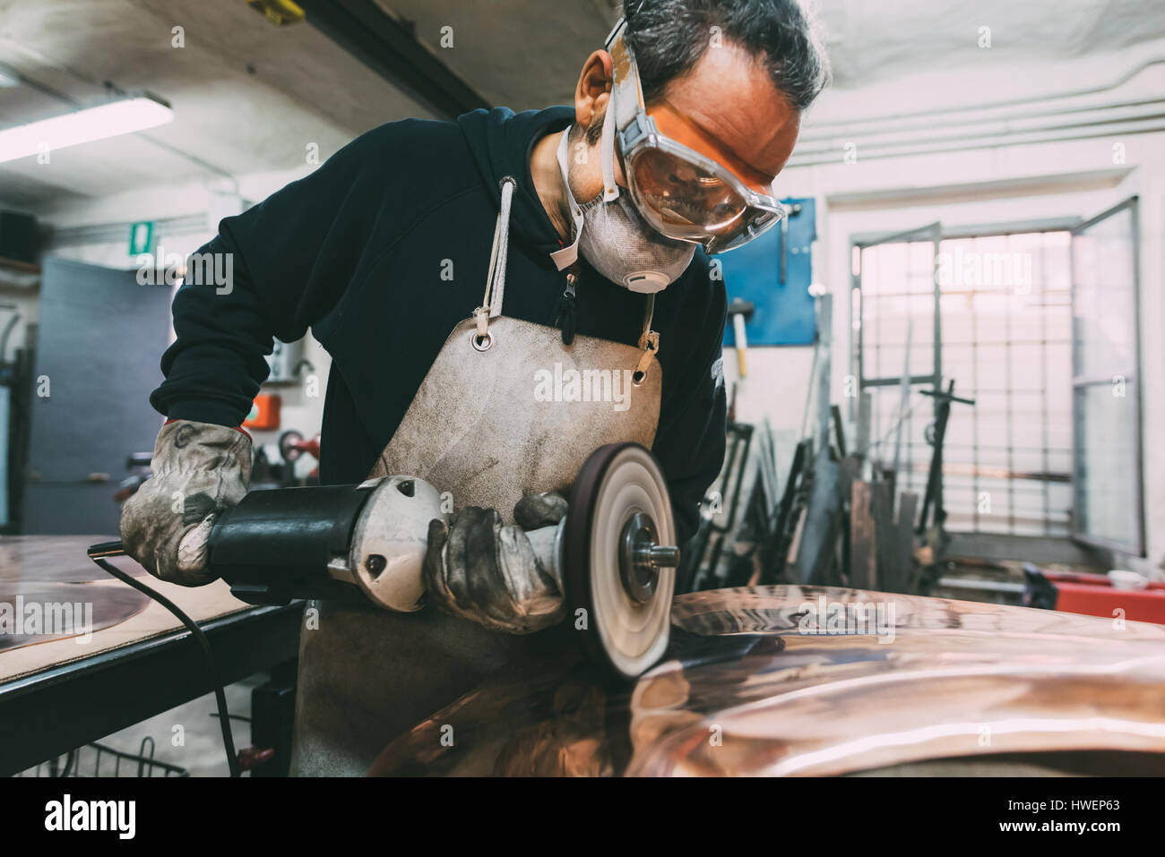Metalworker polishing copper in forge workshop Stock Photo - Alamy