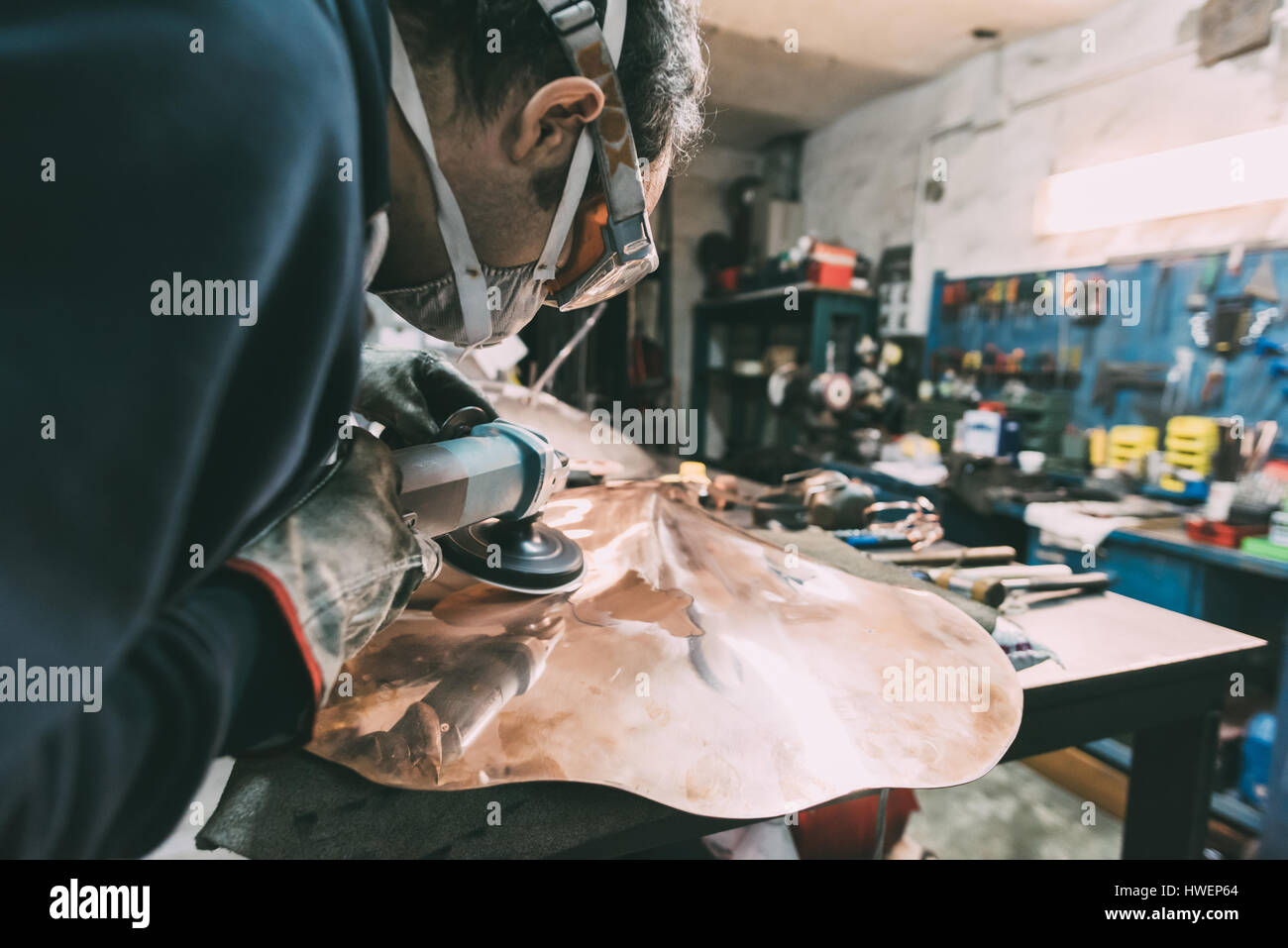 Metalworker polishing copper in forge workshop Stock Photo - Alamy