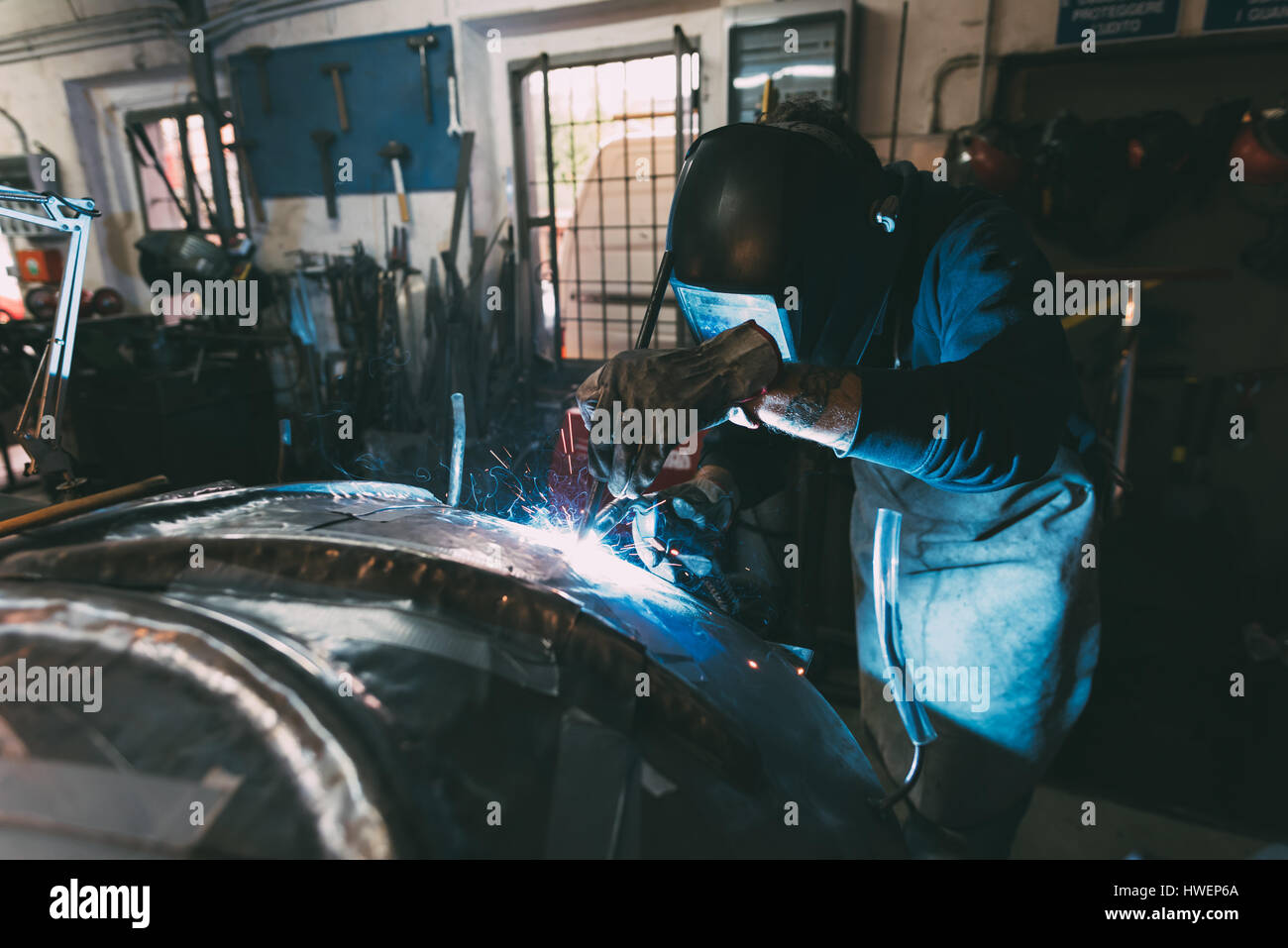 Metalworker in welding mask soldering metal in forge workshop Stock ...