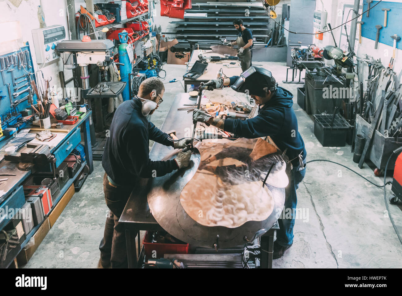Male metalwork team hammering copper at forge workbench Stock Photo - Alamy