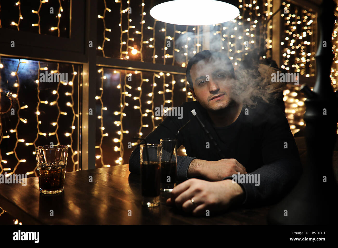 man holding hookah pipe and smoking in a night club Stock Photo - Alamy