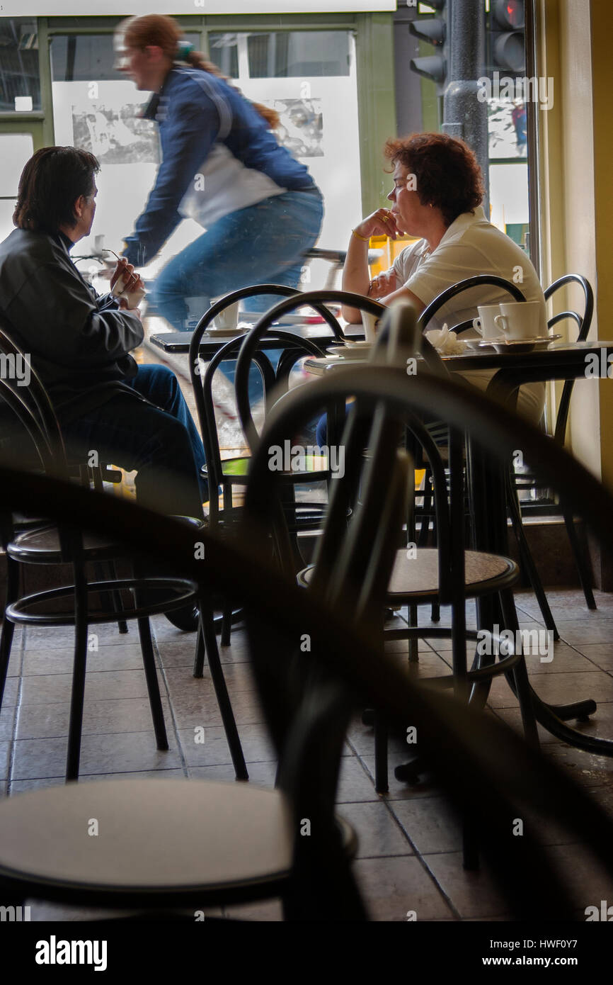 people in cafe with cyclist passing outside Stock Photo - Alamy