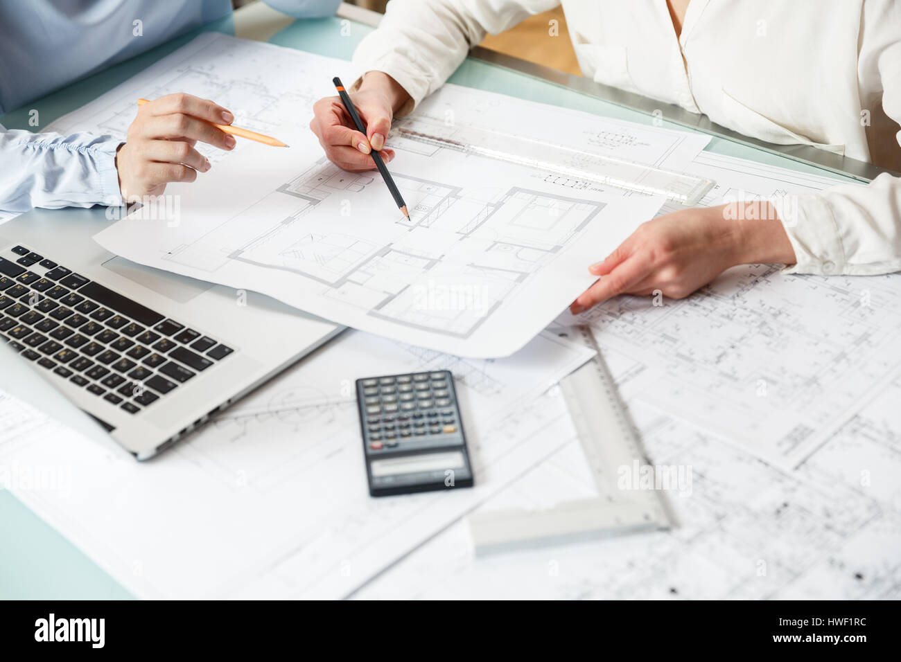 Young female architect and designer working on blueprint project of new ...