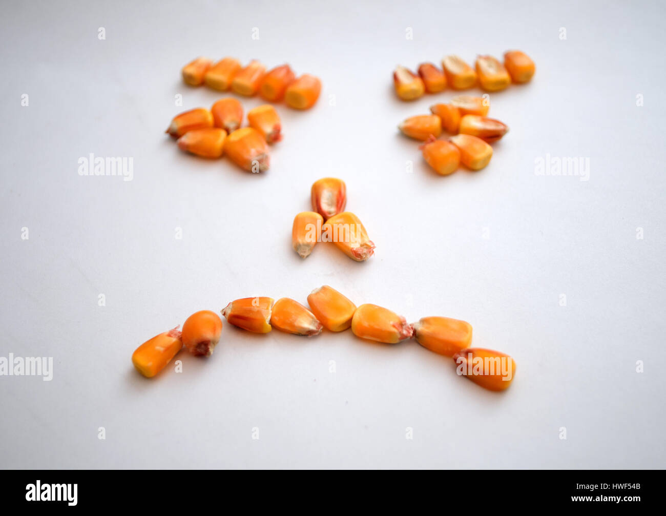 Healthy ecological corn in the form of angry smiley face on a white ...