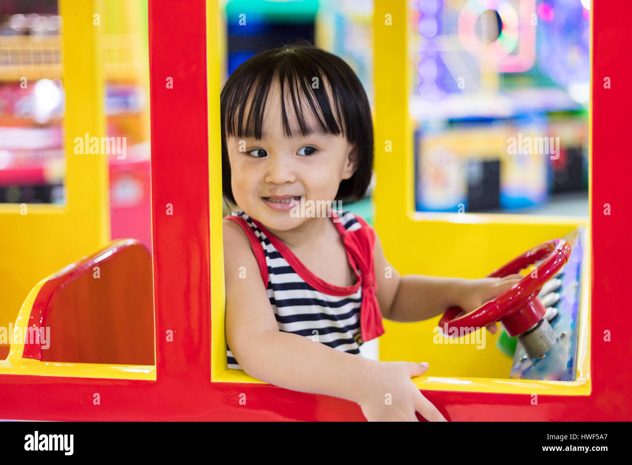 Happy Asian Chinese Little Girl Driving Toy Bus at indoor playground ...