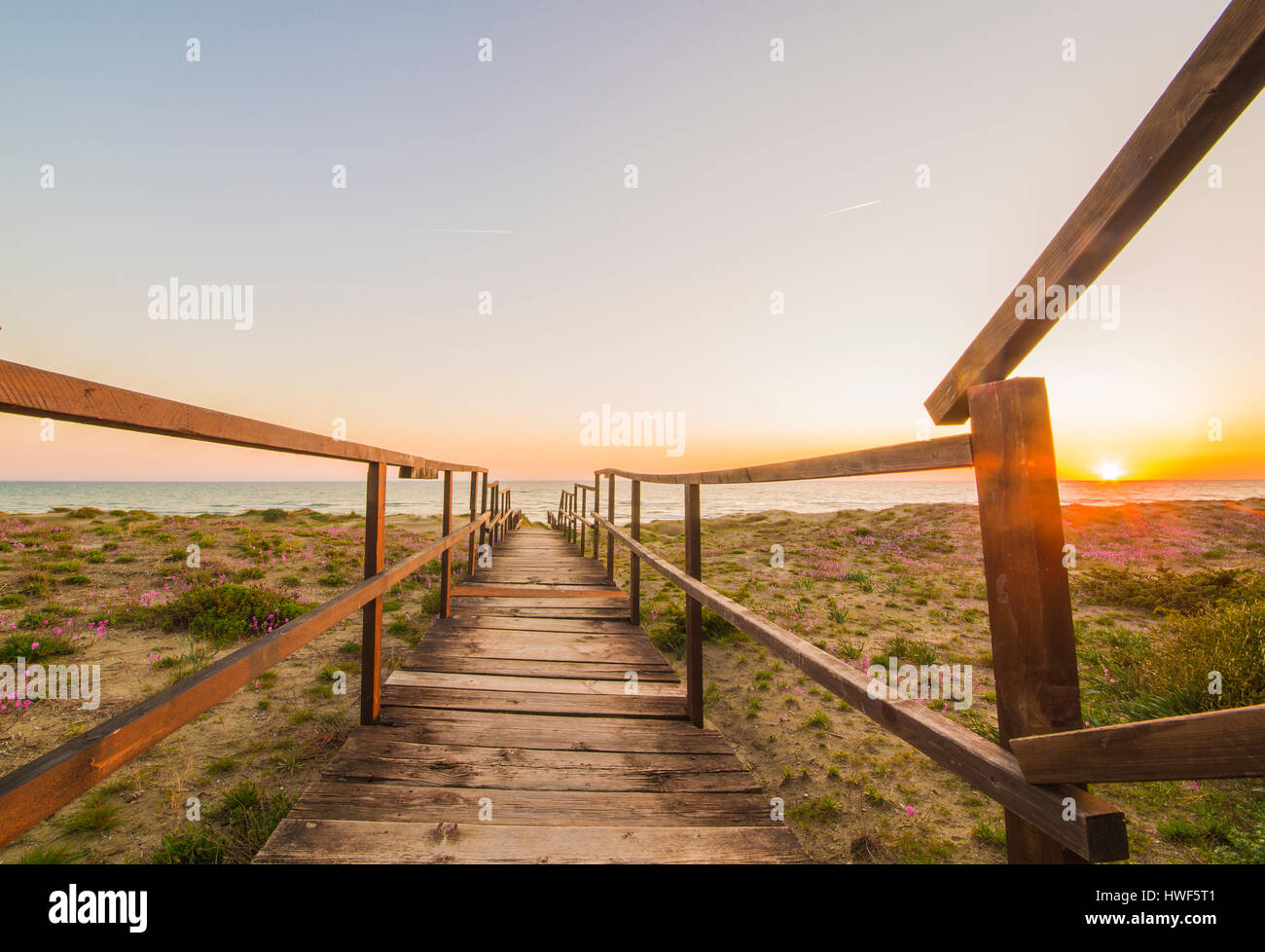 Boardwalk on a beach at sunset Stock Photo - Alamy