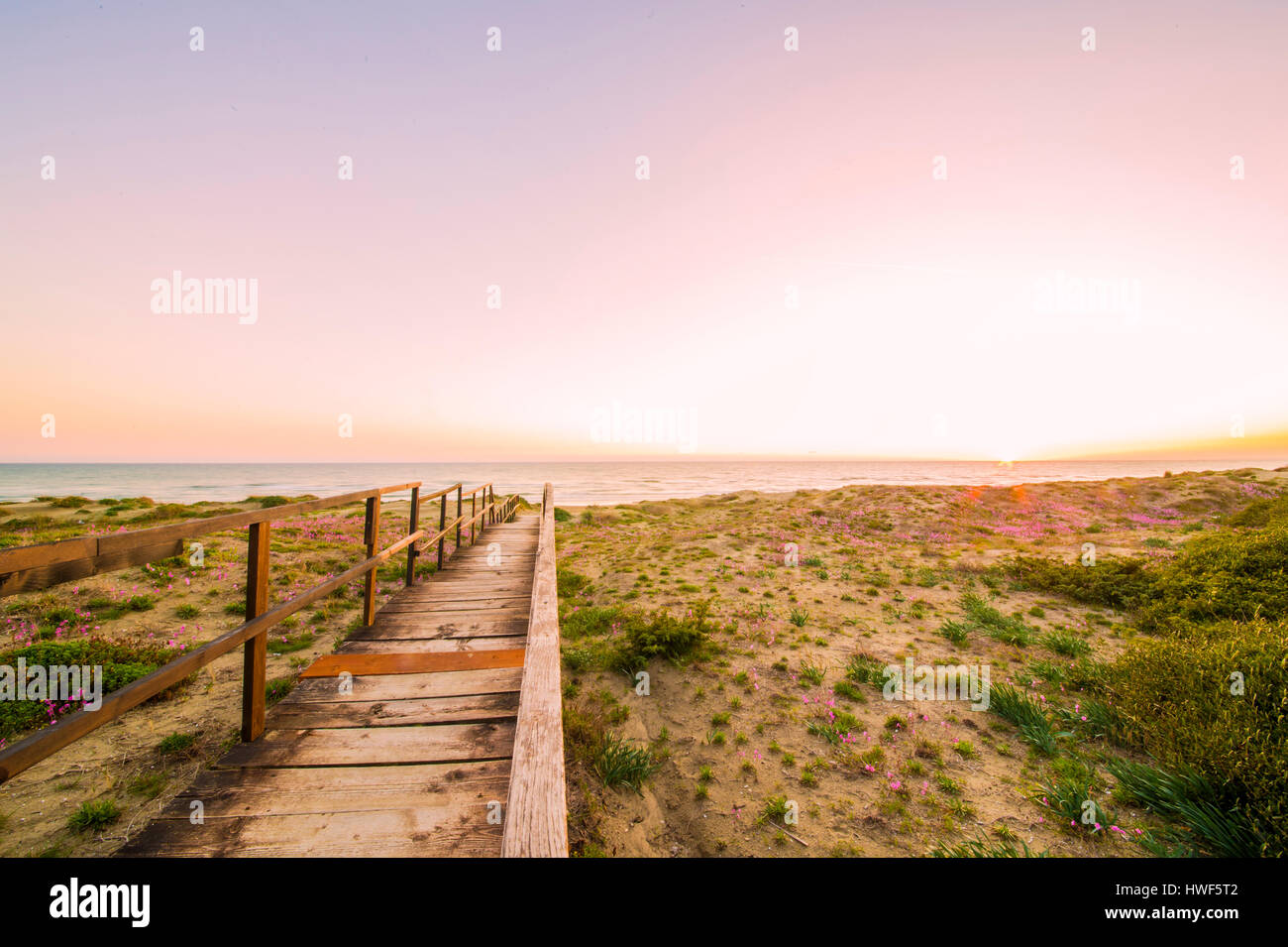 Boardwalk on a beach at sunset Stock Photo - Alamy