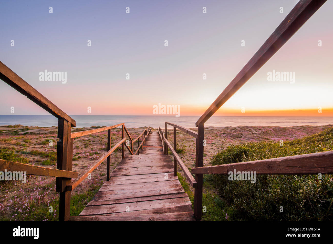 Boardwalk on a beach at sunset Stock Photo - Alamy