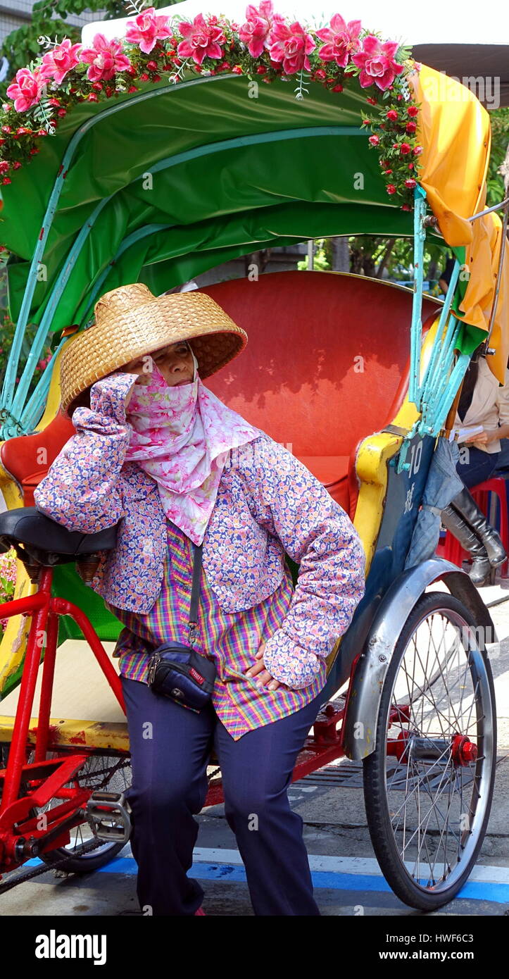 KAOHSIUNG, TAIWAN -- JULY 25, 2015: A female cycle rickshaw driver ...