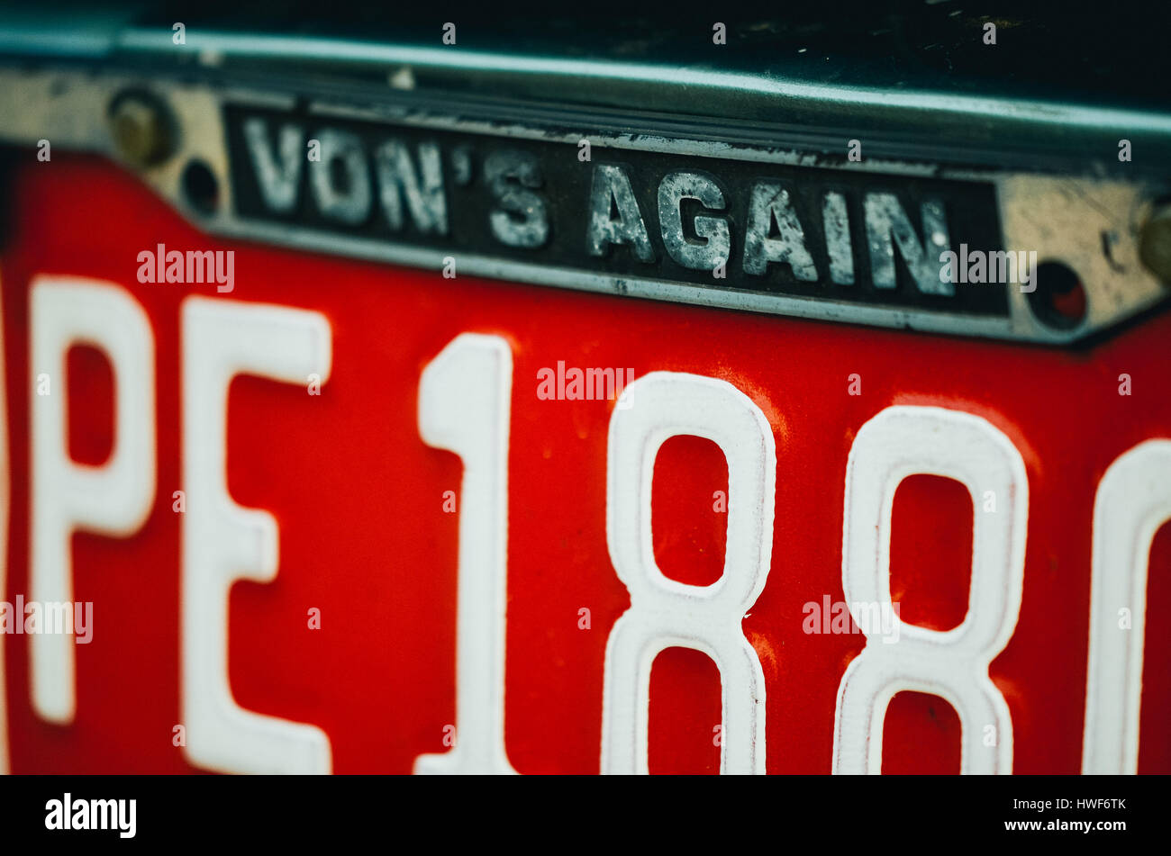 A close up of a license plate. The license plate is red. There is some ...