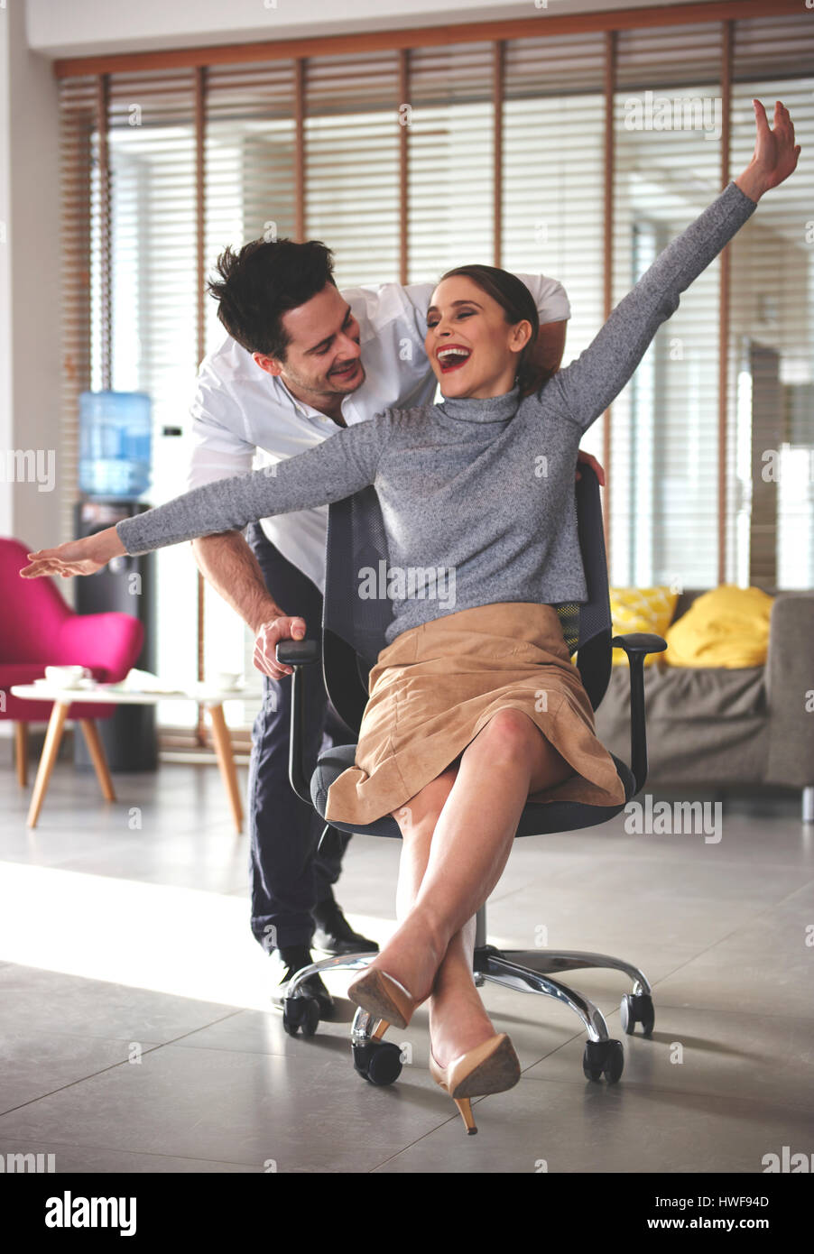 Coworkers having fun with swivel chair Stock Photo - Alamy