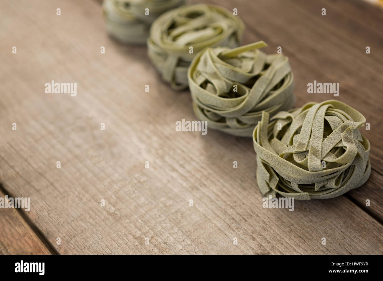 Tagliatelle pasta arranged in a row on wooden background Stock Photo ...