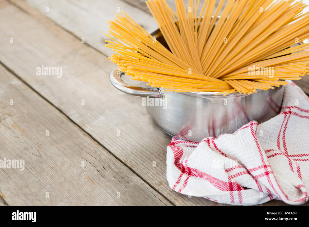 Spaghetti pasta arranged in utensil on wooden surface Stock Photo - Alamy