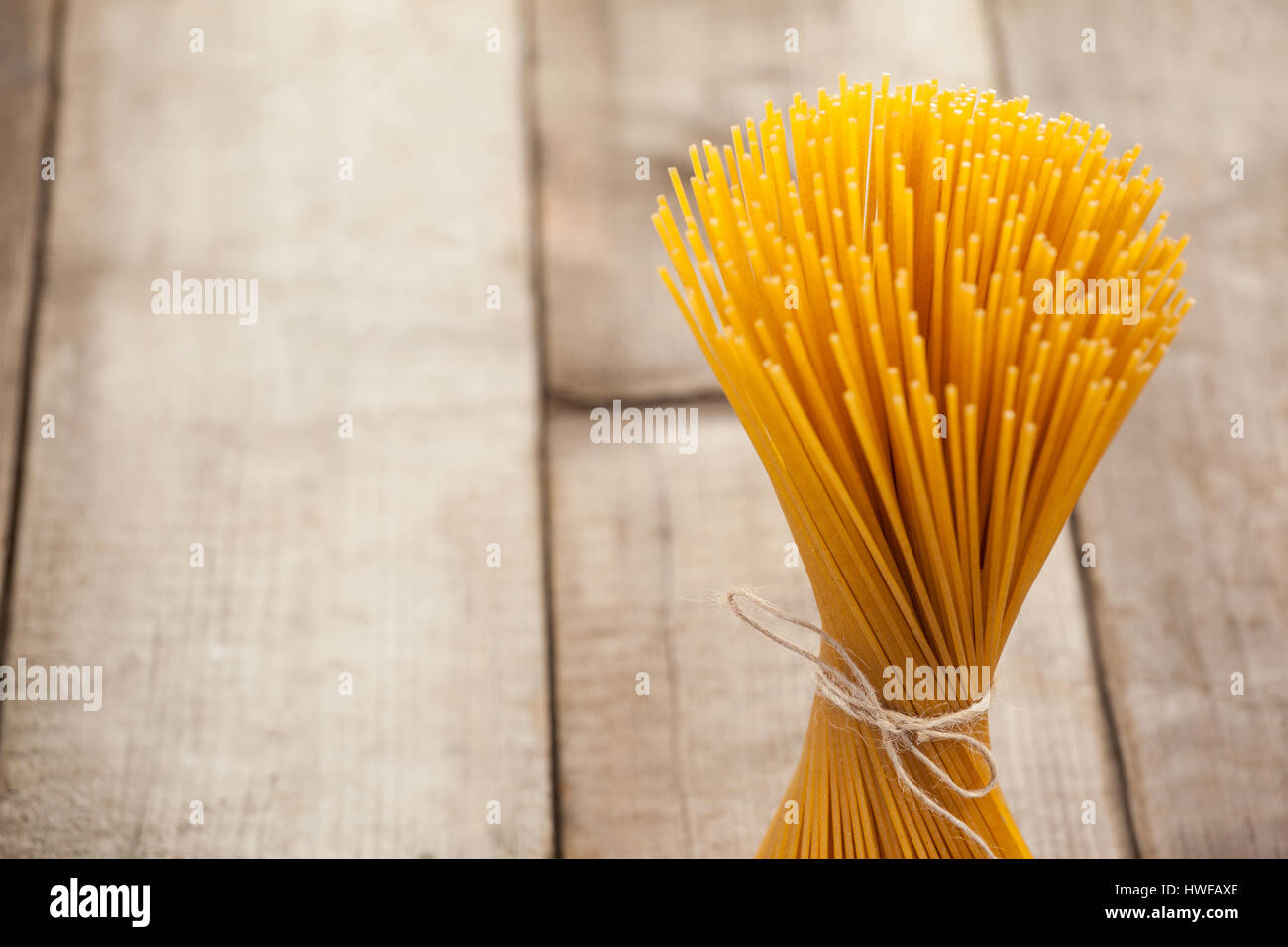 Bundle of raw spaghetti tied with rope on white background Stock Photo ...