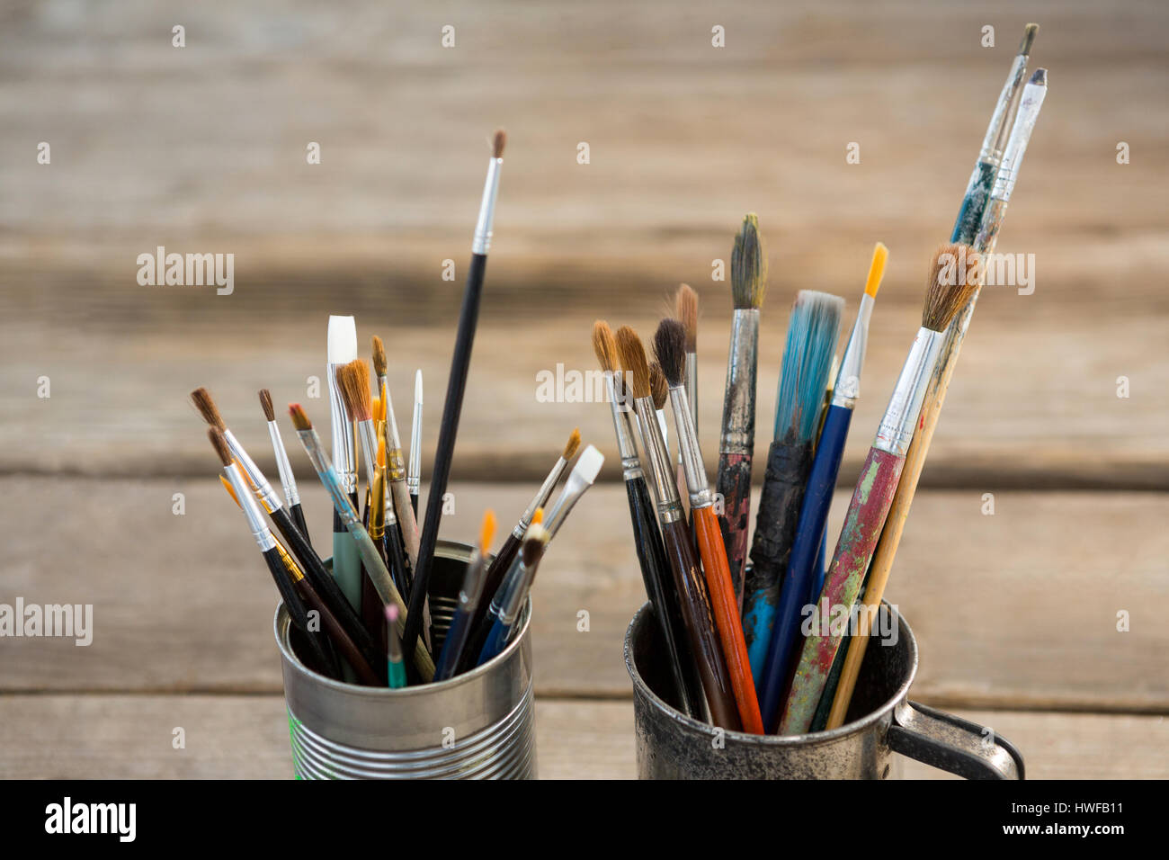 Various paintbrush in container on wooden surface Stock Photo - Alamy