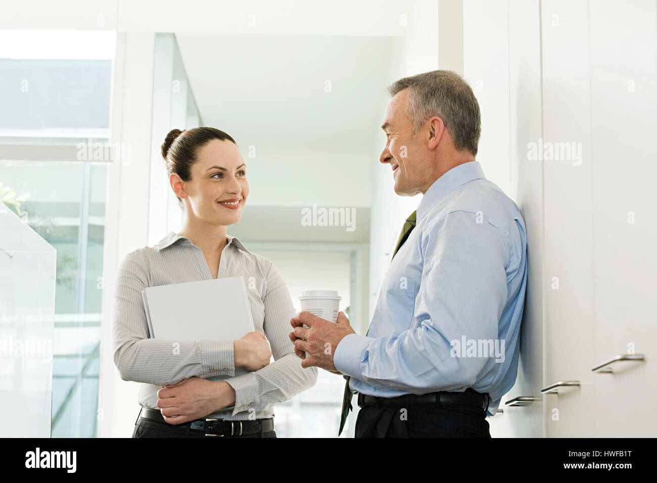 Two business colleagues talking in corridor Stock Photo - Alamy