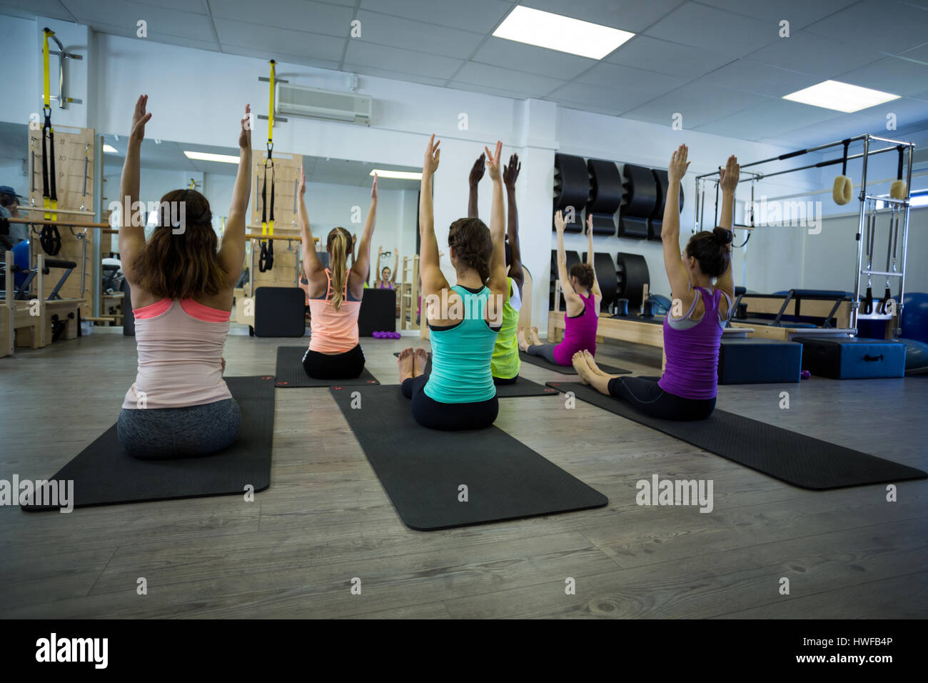 Rear view of women performing stretching exercise in gym Stock Photo ...