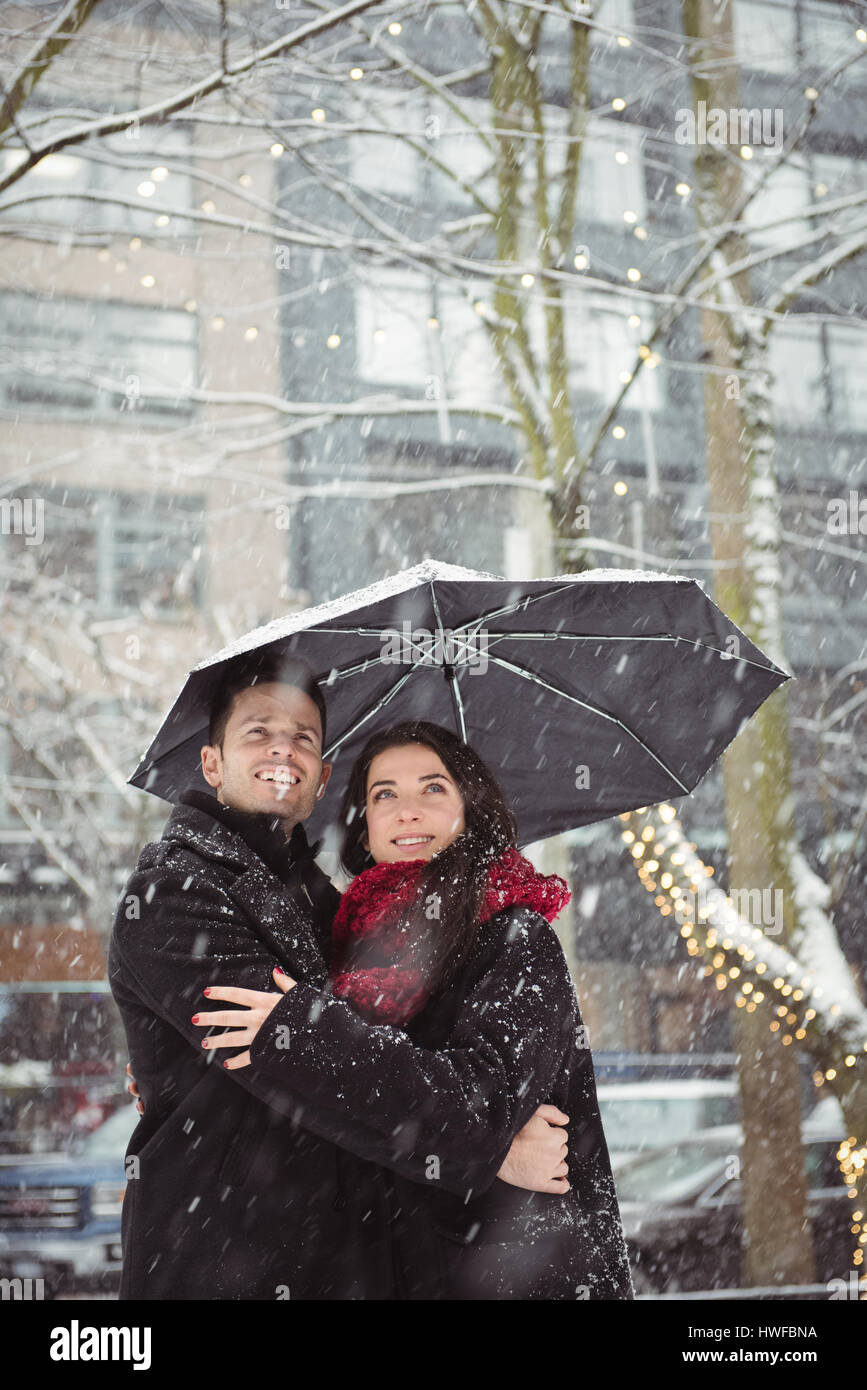 Romantic couple embracing in street during snowfall Stock Photo - Alamy