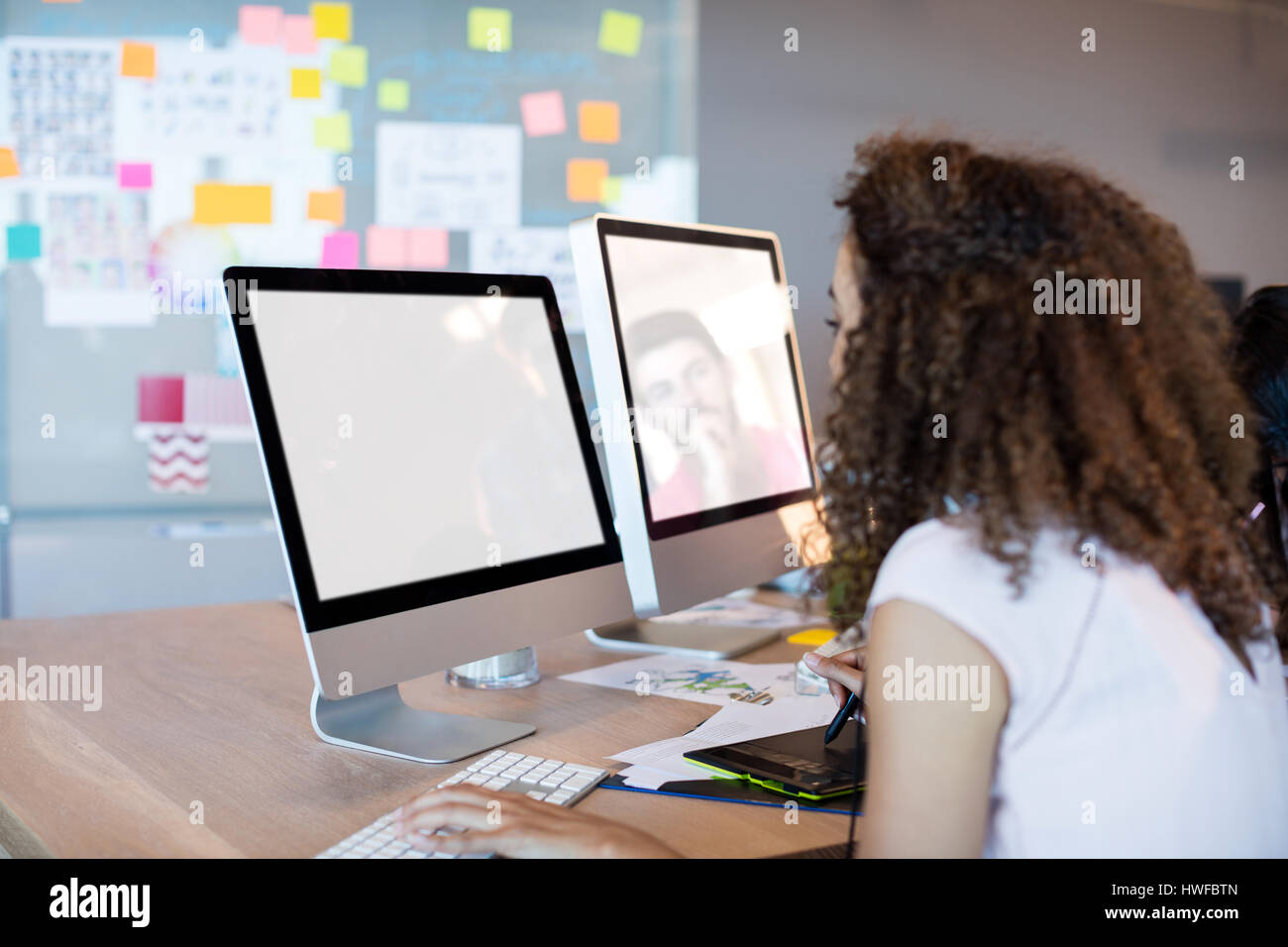 Rear view of woman working on desktop pc in office Stock Photo - Alamy