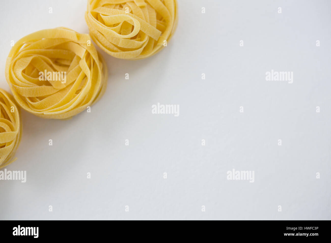 Fettuccine pasta arranged in a row on white background Stock Photo - Alamy