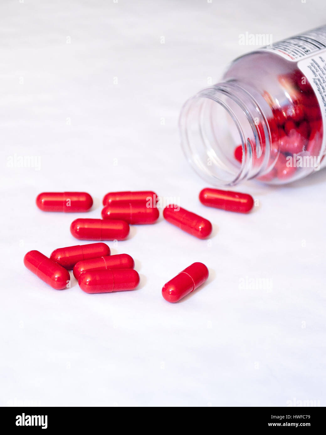 Red vitamin capsules nutritional supplements spilling out of plastic ...