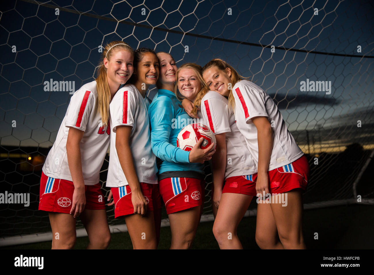 Portrait of smiling soccer team hugging in goal under sunset sky Stock ...
