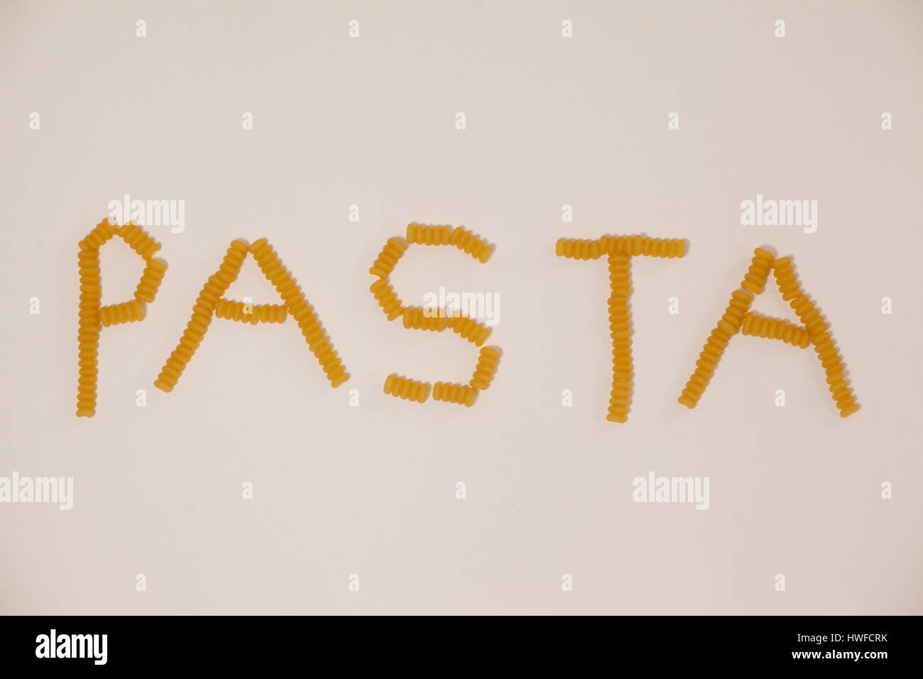 Conchiglie pasta arrange in shape of pasta text on white background ...