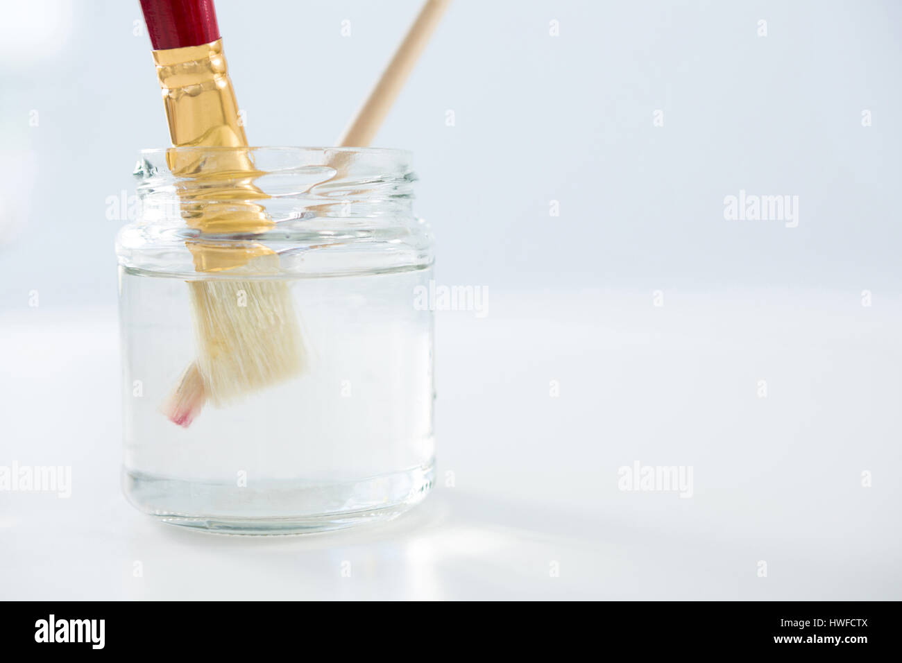 Paintbrushes dipped into water on white background Stock Photo - Alamy