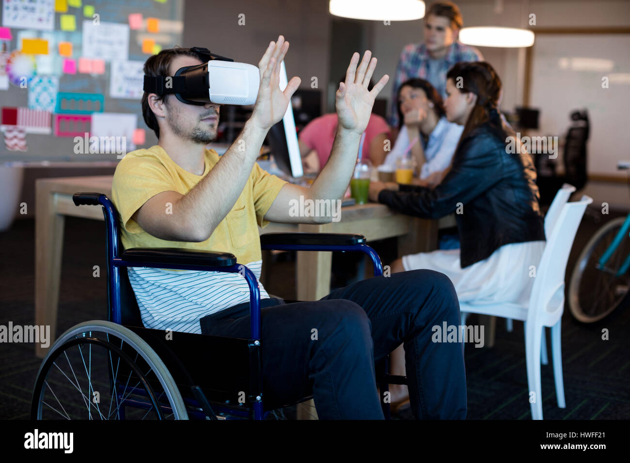 Physically disabled man on wheelchair using VR headset in office Stock ...